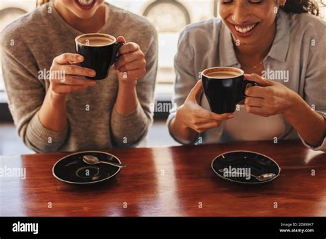 Close Up Of Two Women Sitting At Cafe Table Drinking Coffee Female