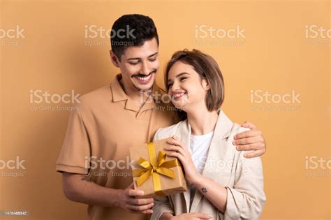 베이지 색상의 선물 상자를 받는 쾌활한 커플 생일 크리스마스 선물 상자 개념 선물에 대한 스톡 사진 및 기타 이미지 선물 커플 스튜디오 촬영 Istock