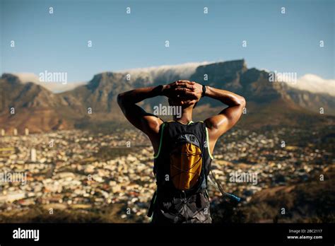 Rear View Of Athletic Man Standing With His Hands Behind Head And Taking A Break After Trail