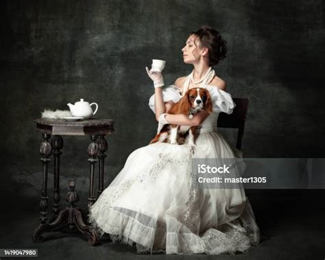 티 타임 개와 함께 아가씨 어두운 배경에 고립 된 르네상스 스타일의 드레스에서 중세 인물의 이미지에있는 젊은 우아한 여성의 빈티지 초상화 30 34세에 대한 스톡 사진 및