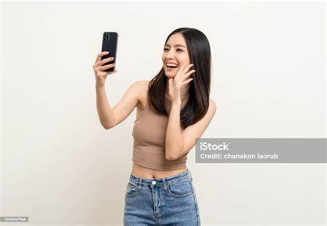 행복한 아름다운 젊은 아시아 여성이 스마트폰 모바일을 사용하여 셀카를 찍고 고립된 흰색 배경에 서서 사진을 찍는다 20 29세에 대한 스톡 사진 및 기타 이미지 Istock