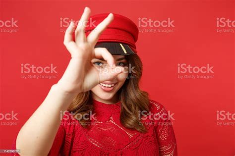 스튜디오에서 밝은 빨간색 배경에 고립 된 확인 제스처 뒤에 보이는 레이스 드레스와 모자를 웃는 젊은 여자의 초상화 사람들은 진심으로 감정 라이프 스타일 개념입니다 복사