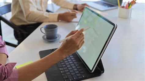 회의실에서 디지털 태블릿을 모형으로 작업하는 스타일러스 펜을 가진 여성 손의 측면도 사진 Unsplash의 컴퓨터 키보드 이미지