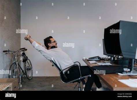 Young Male Hacker Stretching Hands While Working On Computer In Startup