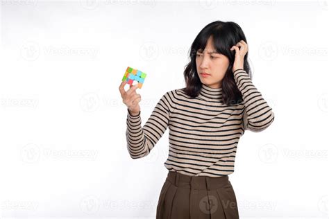 asian woman holding a rubik cube standing on white background solving