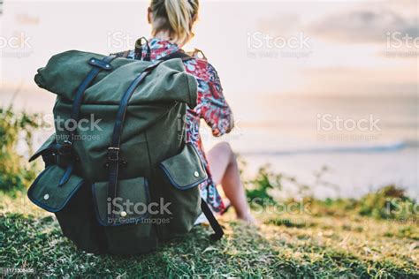 바다 옆에 큰 배낭앉아 황혼 시간에 편안한 캐주얼 옷을 입고 여성 여행자의 백보기 바다 근처에서 시간을 보내는 동안 여성 관광객