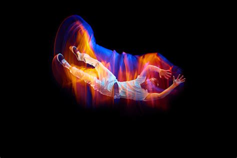 움직이는 춤 비행 점프 댄서 또는 체조 선수가 혼합 된 네온 빛나는 광선으로 검은 배경으로 공중에서 트릭을 수행하는 스튜디오 샷 25 29세에 대한 스톡 사진 및 기타