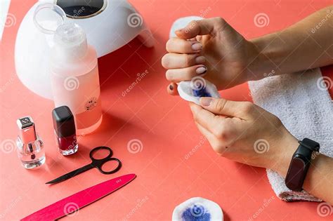 Young Woman Removing Nail Polish From Her Fingernails In A Home