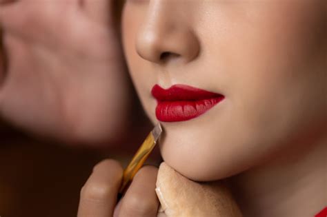 메이크업 아티스트 립 브러쉬를 사용 하 여 아름 다운 모델 입에 빨간 립스틱을 적용 그녀는 그녀의 입에 빨간 립스틱에 박 았 때 매력적인 아름 다운 여 자가 아름 다운 통