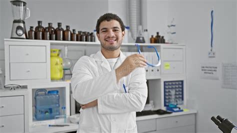 Confident Male Scientist In Lab Coat Adjusting Safety Glasses In Modern Laboratory Setting Stock