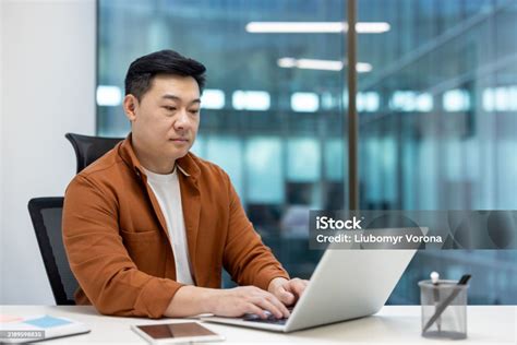 현대적인 사무실 환경에서 집중된 표현으로 노트북으로 작업하고 전문적인 환경에서 디지털 기술과 혁신을 수용하는 아시아 비즈니스
