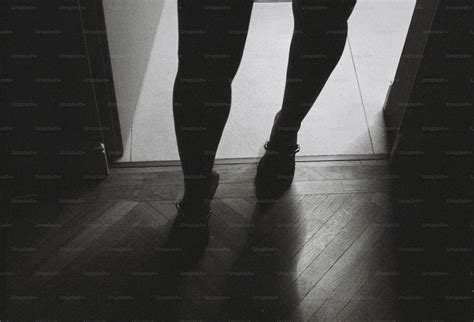 A Woman Standing In A Doorway With Her Legs Crossed Photo Dark