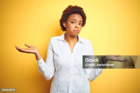 고립 된 노란색 배경에 아프리카 계 미국인 비즈니스 여성은 팔과 손을 들고 단서와 혼란스러운 표정을 지으며 의심 개념 감정에 대한 스톡 사진 및 기타 이미지 Istock