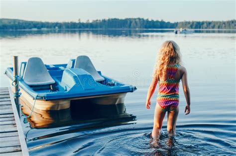 Cute Blonde Girl Walking To Pedal Boat In Lake Water On Sunset Summer