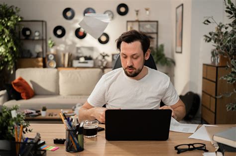 갈색 머리는 직장에서 일하고 문서를 검토합니다 그는 불필요한 모든 페이지를 버립니다 테이블에 커피 한 잔과 문구류가 있습니다 고객에 대한 스톡 사진 및 기타 이미지 Istock