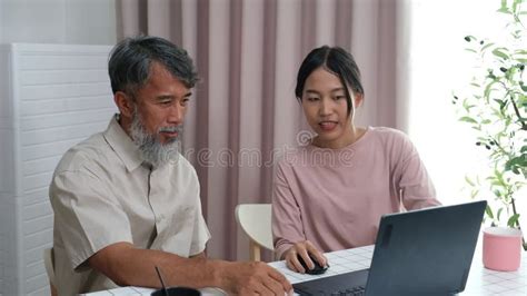 Granddaughter Teaching Elderly Uncle To Use Laptop For News Updates In Living Room Stock Video