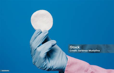 의료 장갑을 낀 남자가 면 패드를 들고 있습니다 파란색 배경입니다 의료 및 미용 콘텐츠 건강관리와 의술에 대한 스톡 사진 및 기타 이미지 건강관리와 의술 고무 장갑