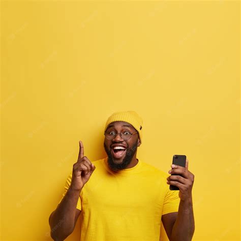 Free Photo Cheerful Man Points Index Finger Above Creats Own Blog Surfes Social Media On