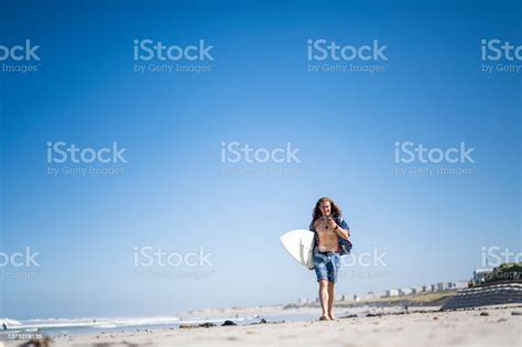 그의 휴대 전화를 확인 해변에서 서핑 보드와 함께 걷는 미소 남성 서퍼 20 24세에 대한 스톡 사진 및 기타 이미지 20 24세 Brand Name Smart
