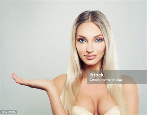 건강 한 피부와 흰색 바탕에 오픈 손에서 빈 복사본 공간을 보여주는 금발 머리 여자 스파 모델 미소 페이셜 트리트먼트 제품