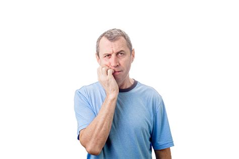 중년 남성이 손가락 손톱을 물고 긴장된 몸짓으로 하얀 배경에 고립되어 있다고 강조했다 불안한 중년 노동자 는 절망적 인 혐오감을 느낀다 감정에 대한 스톡 사진 및 기타