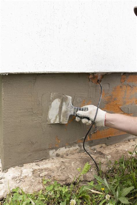A Worker Plasters The Foundation With Cement Plaster And Glues In The