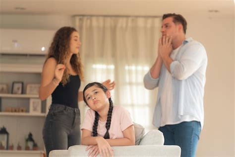 Niña molesta e infeliz sentada en un sofá atrapada en medio de la tensión por la discusión de