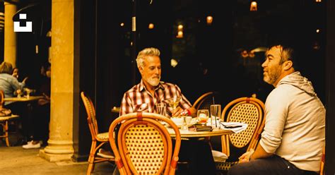 빨간색과 흰색 격자 무늬 드레스 셔츠를 입은 남자가 갈색 나무 의자에 앉아 사진 Unsplash의 무료 Eating 이미지