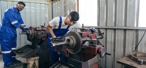 금속 선반 기계를 사용하는 다양성 정비사 또는 금속 세공인은 자동차 수리 차고에서 자동차 디스크 브레이크를 연마합니다 자동차 유지 보수 및 차량 부품 개념 검사 20 24
