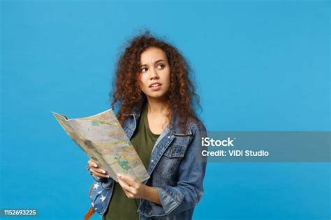 데님 옷에 젊은 아프리카계 미국인 소녀 사춘기 학생 배낭 개최 지도 파란색 벽 배경 스튜디오 초상화에 고립 고등학교 대학 대학 개념에서 교육 복사 공간을 모의 합니다 가방에