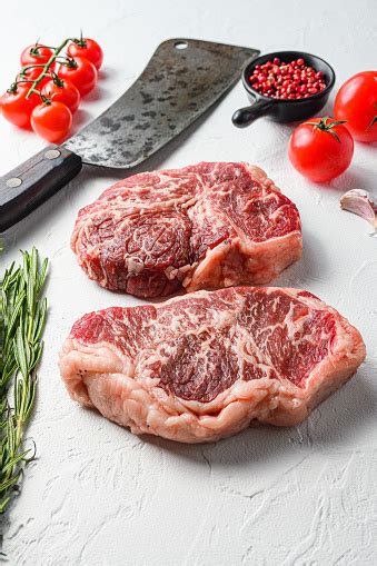 유기농 톱 블레이드 스테이크 조미료 로즈마리 정육점 칼을 곁들인 생 소고기 흰색 텍스처 배경 측면 보기입니다 0명에 대한 스톡 사진 및 기타 이미지 Istock