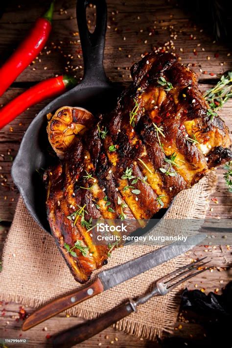 소박한 빈티지 나무 테이블 고기를 곁들인 육즙이 많은 돼지 갈비 체리 토마토 향신료 포크와 나이프 후추 로즈마리 바 질 등 어두운 배경 겨자 상단 사이드 뷰 샷 0명에 대한