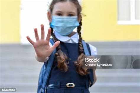 의료 용 마스크의 여학생은 코로나 바이러스와 거리 학습을 중지 제스처를 보여줍니다 아이들은 새로운 정상으로 학교에 간다 코로나바이러스 학교로 돌아가기 붐비는 장소에서 안전의