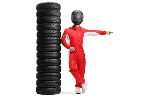 타이어 더미에 헬멧을 기대고 흰색 배경에 고립 된 가리키는 레이서의 전체 길이 초상화 자동차 경주 선수에 대한 스톡 사진 및 기타 이미지 자동차 경주 선수 스포츠 헬멧