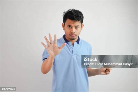 손 제스처를 가진 매력적인 아시아 남자는 흰색 배경에 격리된 파란색 티셔츠를 입고 옆에서 복사 공간을 가리키면서 거부 또는 금지를 포즈를 취합니다 25 29세에 대한 스톡