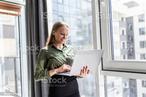 사무실에 서서 창문 근처에서 노트북을 들고 있는 젊은 사업가 노트북에 대한 스톡 사진 및 기타 이미지 노트북 노트북 사용하기 명랑한 Istock