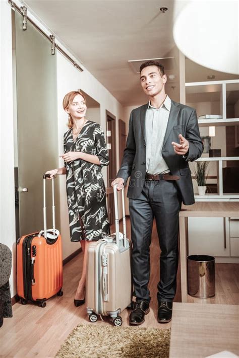 Husband And Wife Caring Their Luggage While Entering Hotel Room Stock