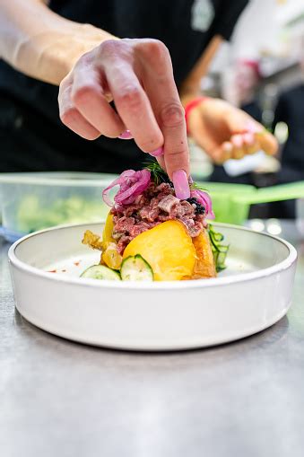 신선한 허브로 화려한 접시를 장식하는 손의 클로즈업 이 요리는 생생한 녹색 노란색 및 빨간색 요소를 특징으로 하여 미식가 요리 프레젠테이션을 제안합니다 가루로 빻은에 대한