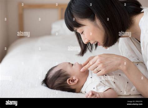 Mother Cradling Baby Lying On Back On Bed Stock Photo Alamy