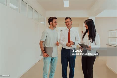 감독은 대기업의 현대적이고 넓은 복도에서 비서 및 젊은 프로그래머와 대화를 나누며 다양한 비즈니스 주제와 프로젝트에 대해 논의합니다 감독에 대한 스톡 사진 및 기타 이미지