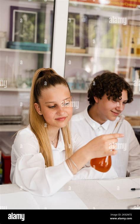 chemistry lesson schoolgirl and classmates holds flask for experiments