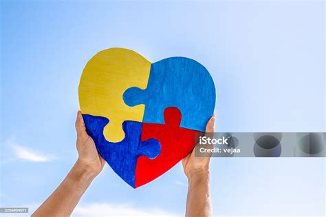 세계 자폐증 인식의 날 자폐증 스펙트럼 장애 개념 성인과 어린이의 손은 푸른 하늘 배경에 다채로운 색칠 된 퍼즐 심장을 함께 들고 있습니다 스페인에 대한 스톡 사진 및 기타
