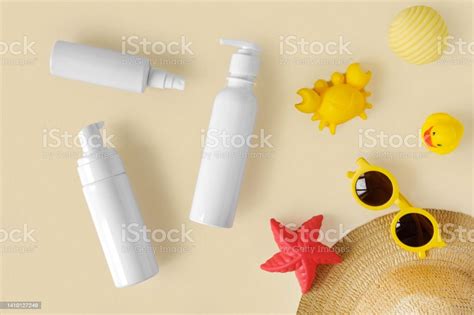 중립 배경에 선 스크린 로션 튜브 태양 보호와 어린이 선글라스와 베이지 색 테이블에 샌드 박스 장난감의 플라스틱 병 어린이 피부