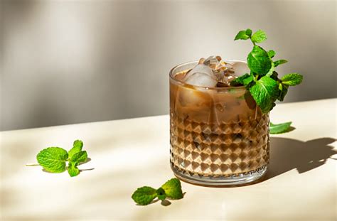 보드카 커피 리큐어 민트 슈납스 베이지색 배경에 크림과 얼음 단단한 빛 그림자 패턴 복사 공간이 있는 민트 화이트 러시아 알코올