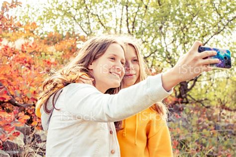 쾌활한 십대 소녀 야외에서 휴대 전화로 셀카를 찍고 2명에 대한 스톡 사진 및 기타 이미지 2명 가을 긍정적인 감정 표현