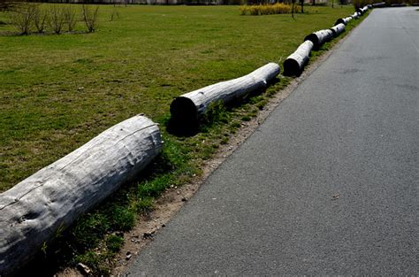 회색 오래된 통나무 주차에 대한 보호로 차선 사이 비포장 도로 및 사이클 경로로 주차장의 운송 솔루션 정원의 아스팔트 표면과 잔디밭 가드레일에 대한 스톡 사진 및 기타