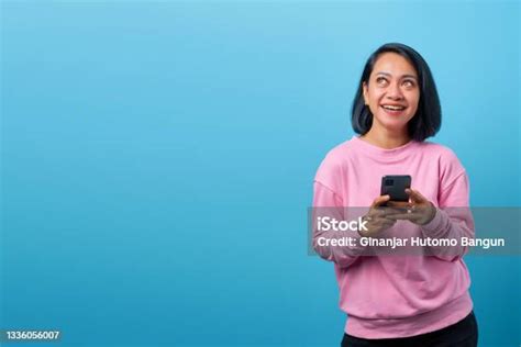 스마트 폰을 들고 있는 쾌활한 젊은 아시아 여성과 행복한 옆으로 보고 30 34세에 대한 스톡 사진 및 기타 이미지 30 34세 Brand Name Smart