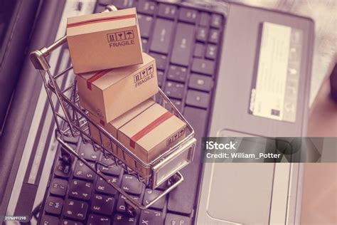 온라인 쇼핑 전자 상거래 및 고객 경험 개념 랩톱 컴퓨터 키보드의 상자와 쇼핑 카트는 소비자 또는 구매자가 집에서 상품과 서비스를 구매하거나 구매하는 것을 묘사합니다 조달