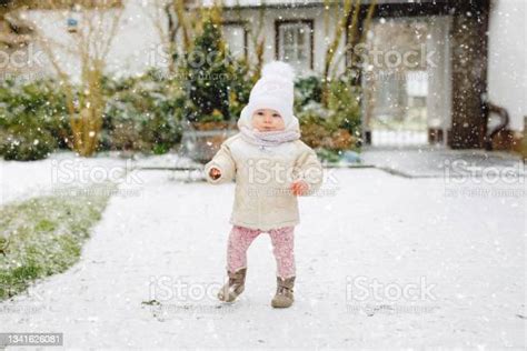 눈을 통해 겨울에 야외에서 첫 걸음을 내딛는 행복한 어린 소녀 귀여운 유아 학습 산책 추운 눈 덮인 날에 재미를 아이 아기의 첫 번째 눈 활동 야외에서 겨울 산책 걷기에