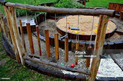 맨발로 걸을 수있는 좌석과 촉각 산책로 중간에 모래 구덩이가 있습니다 나무 팰리세이드와 매달린 나무 카리용으로 구성된 어린이